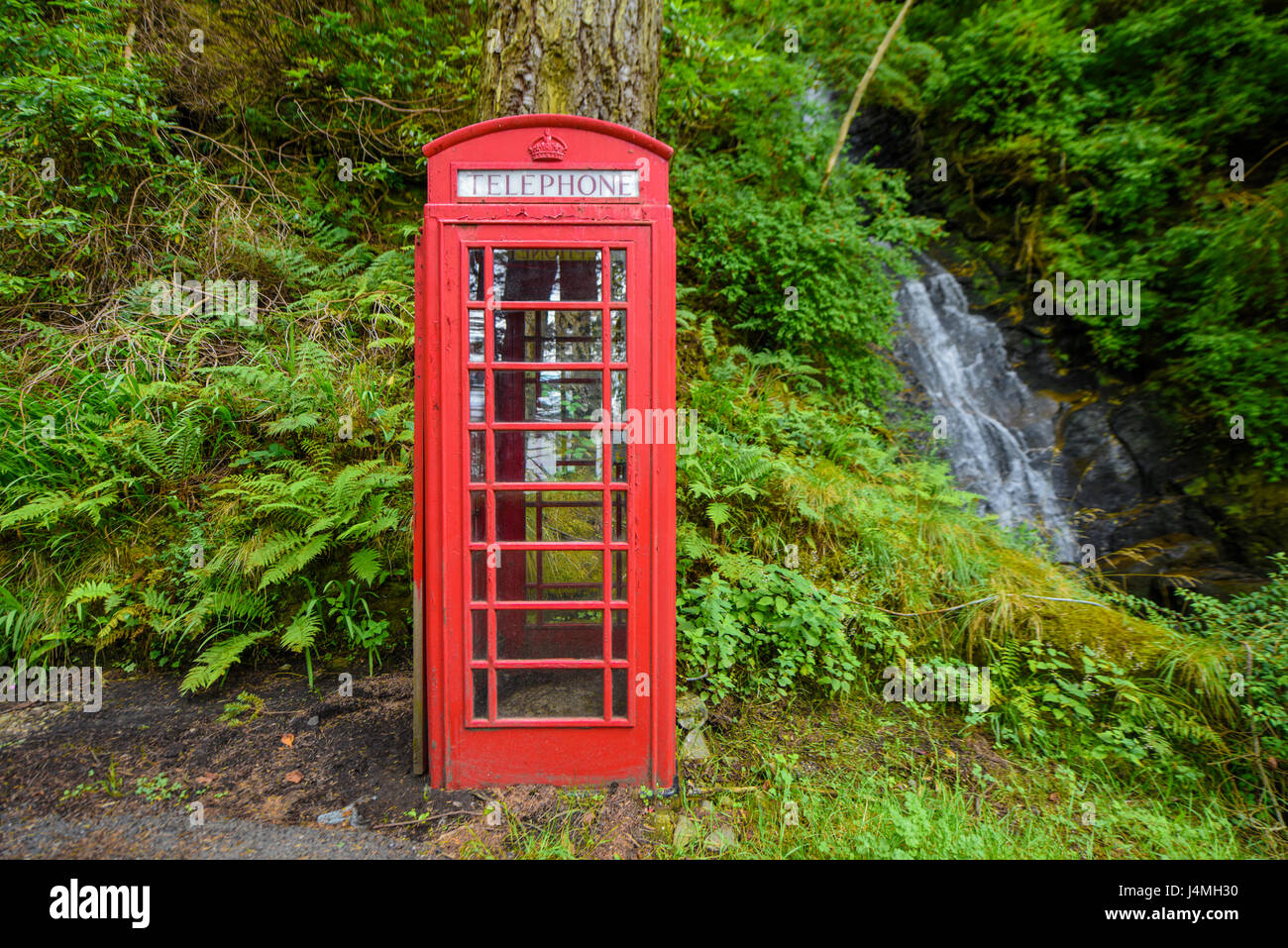 Red telephone box in the forest next to a waterfall. Scotland, United ...