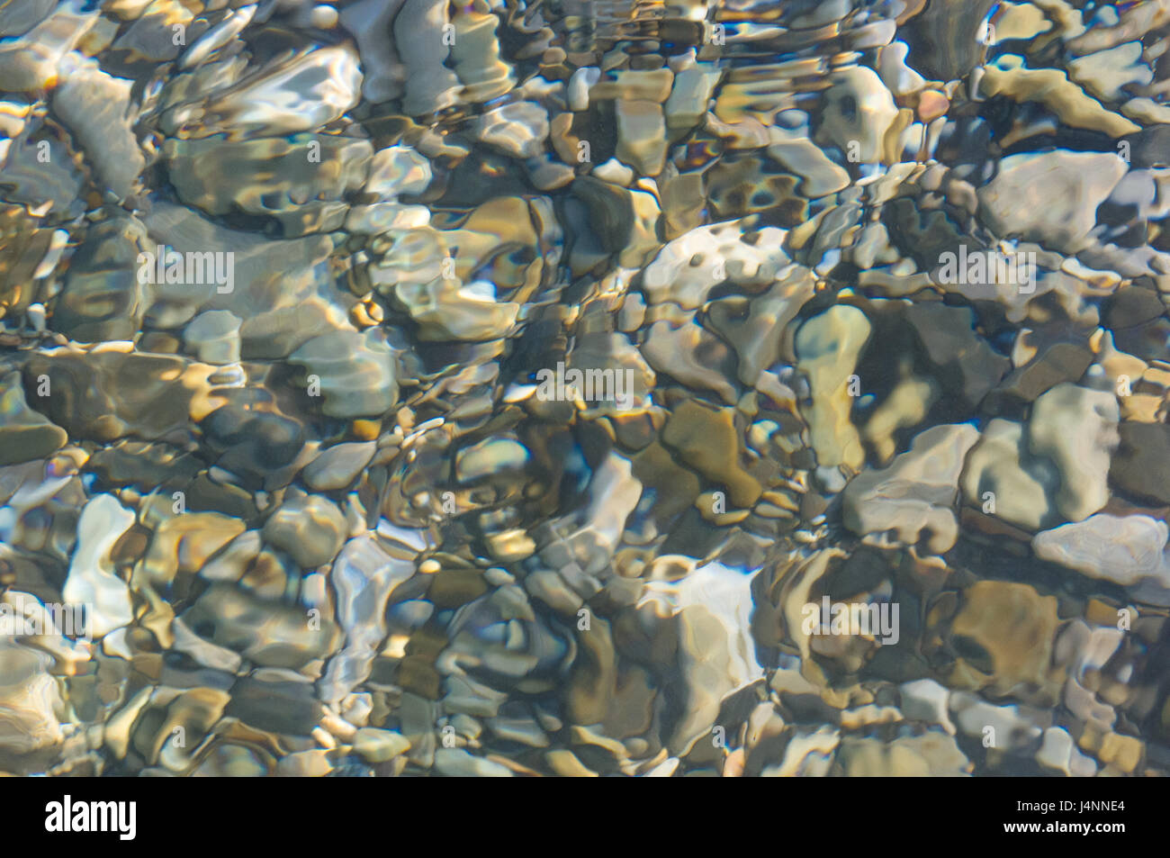 sea pebble beach with multicoloured stones, transparent waves with foam ...
