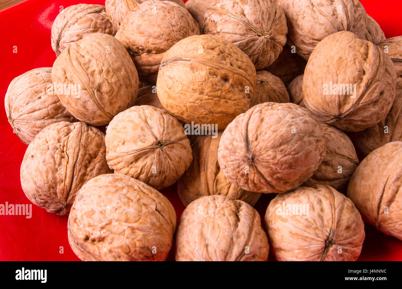 walnuts in red plate on wooden background Stock Photo - Alamy