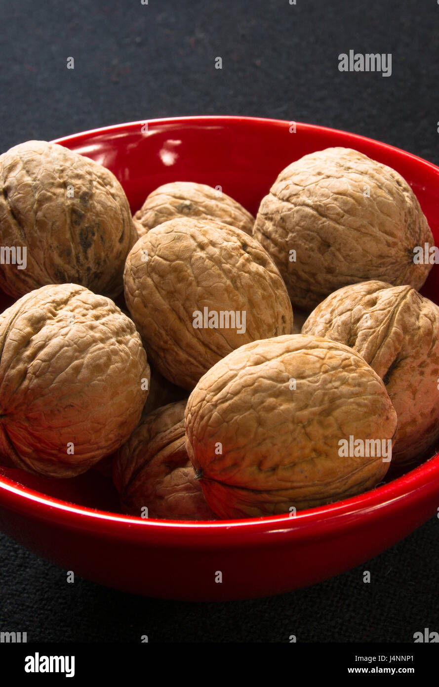walnuts in red plate on black background Stock Photo - Alamy
