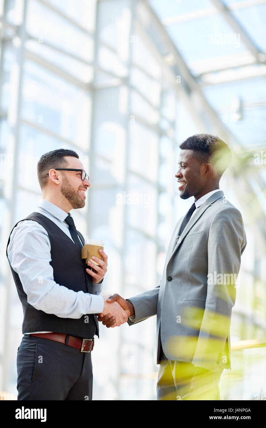 Portrait of smiling businessman greeting African-American partner by ...
