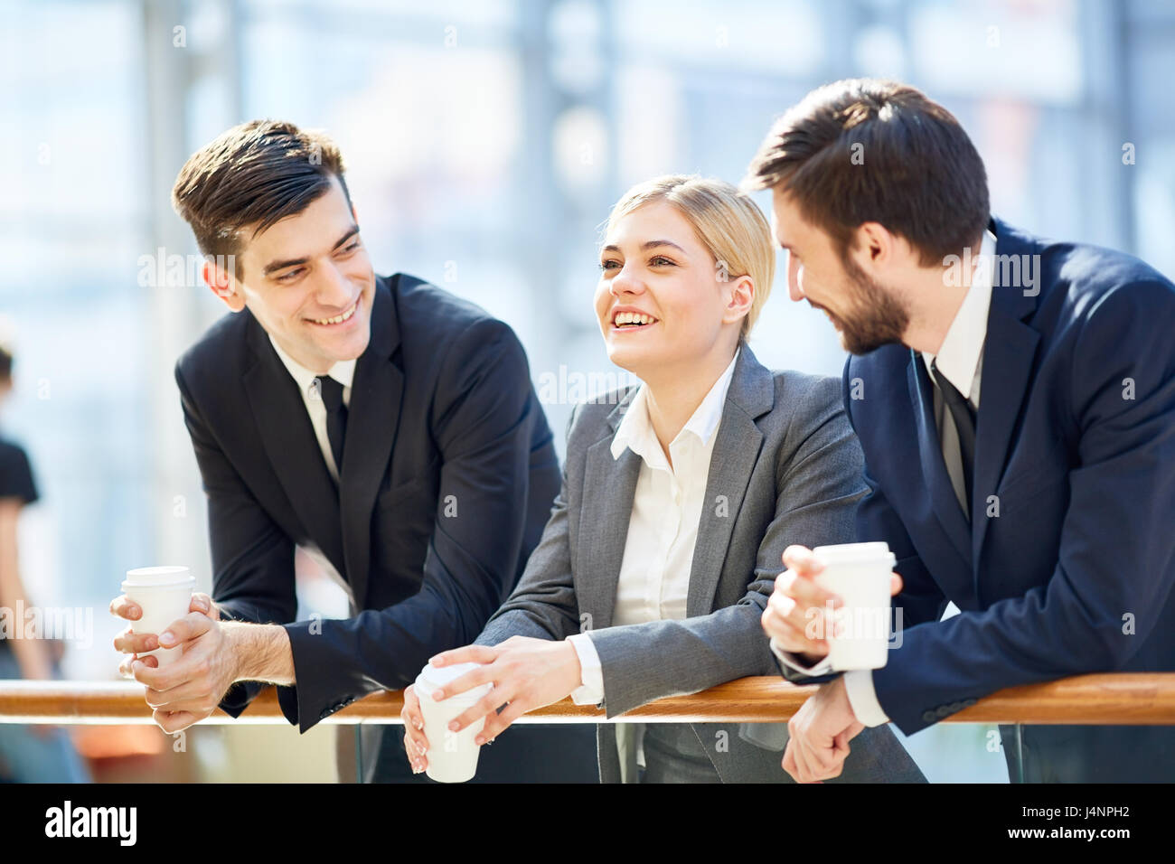 Portrait of three business people, one woman and two men, smiling ...