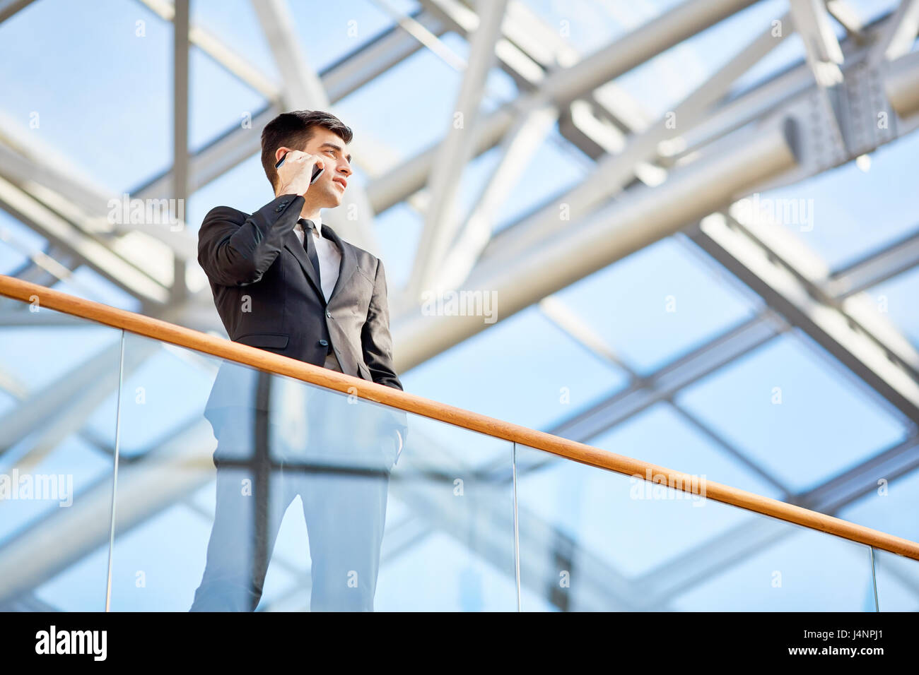 Low angle portrait of powerful young businessman talking by smartphone ...
