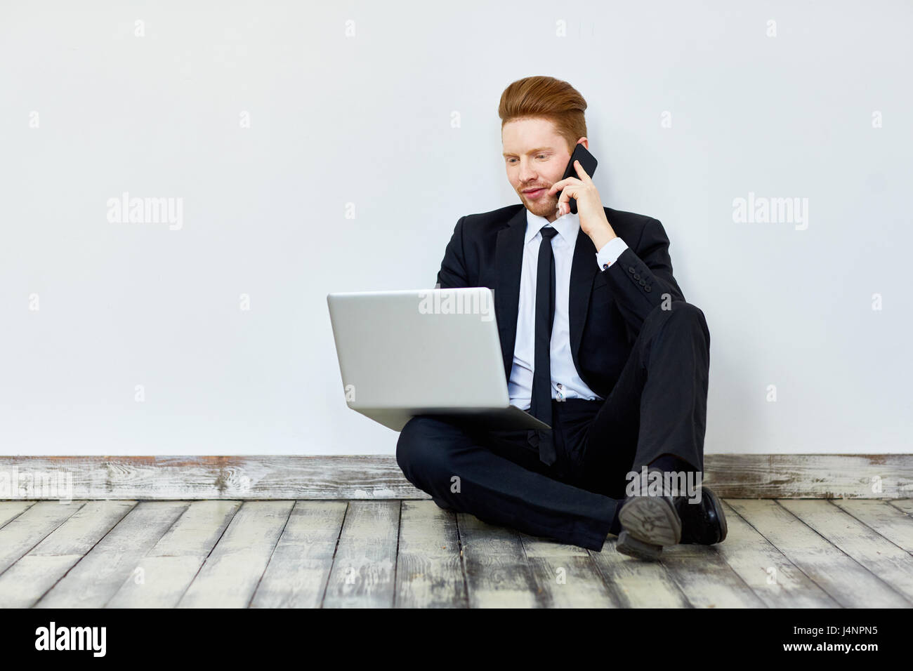 Salesman with laptop speaking to client on cellphone Stock Photo - Alamy