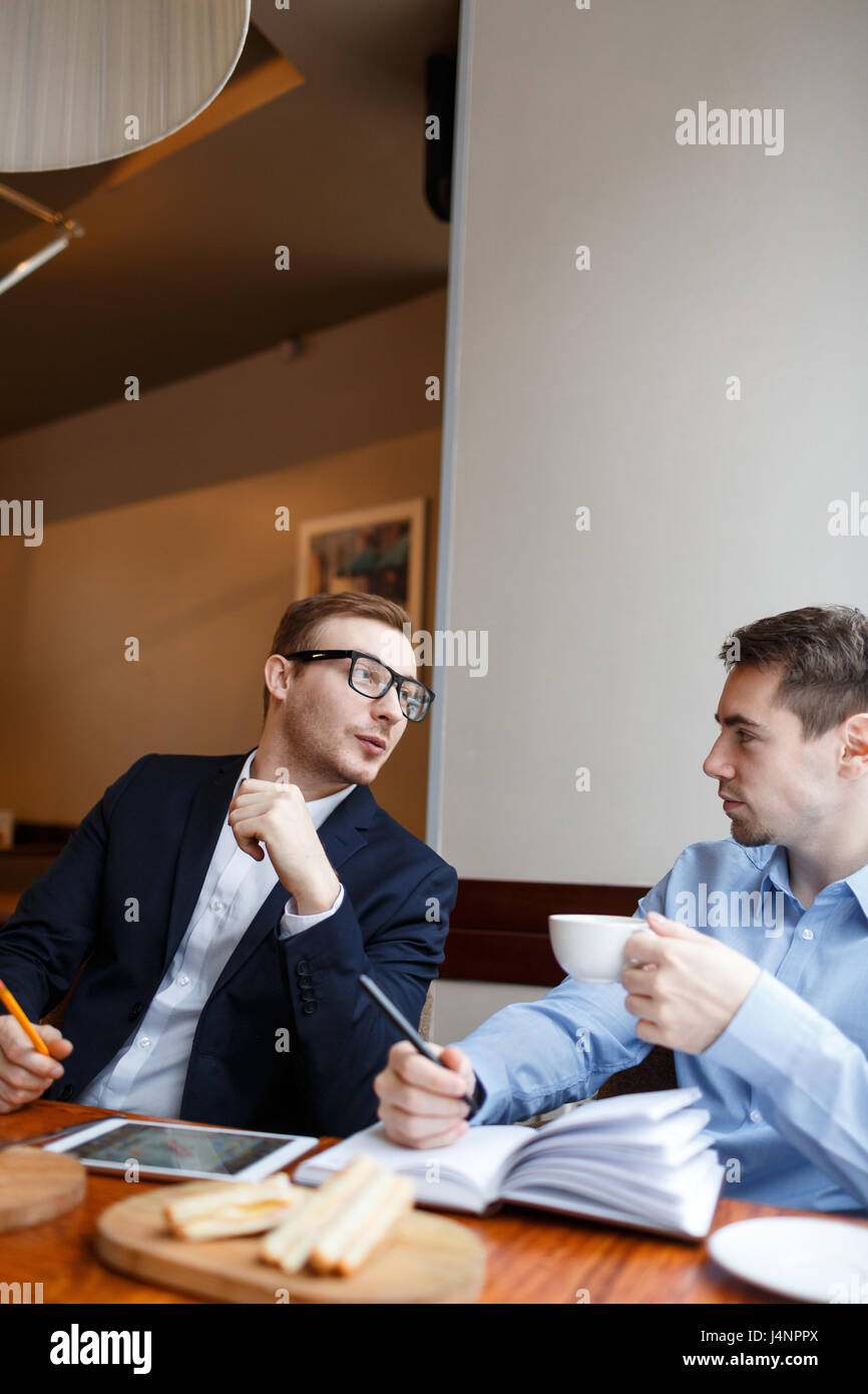Portrait of two business people discussing work during casual meeting ...
