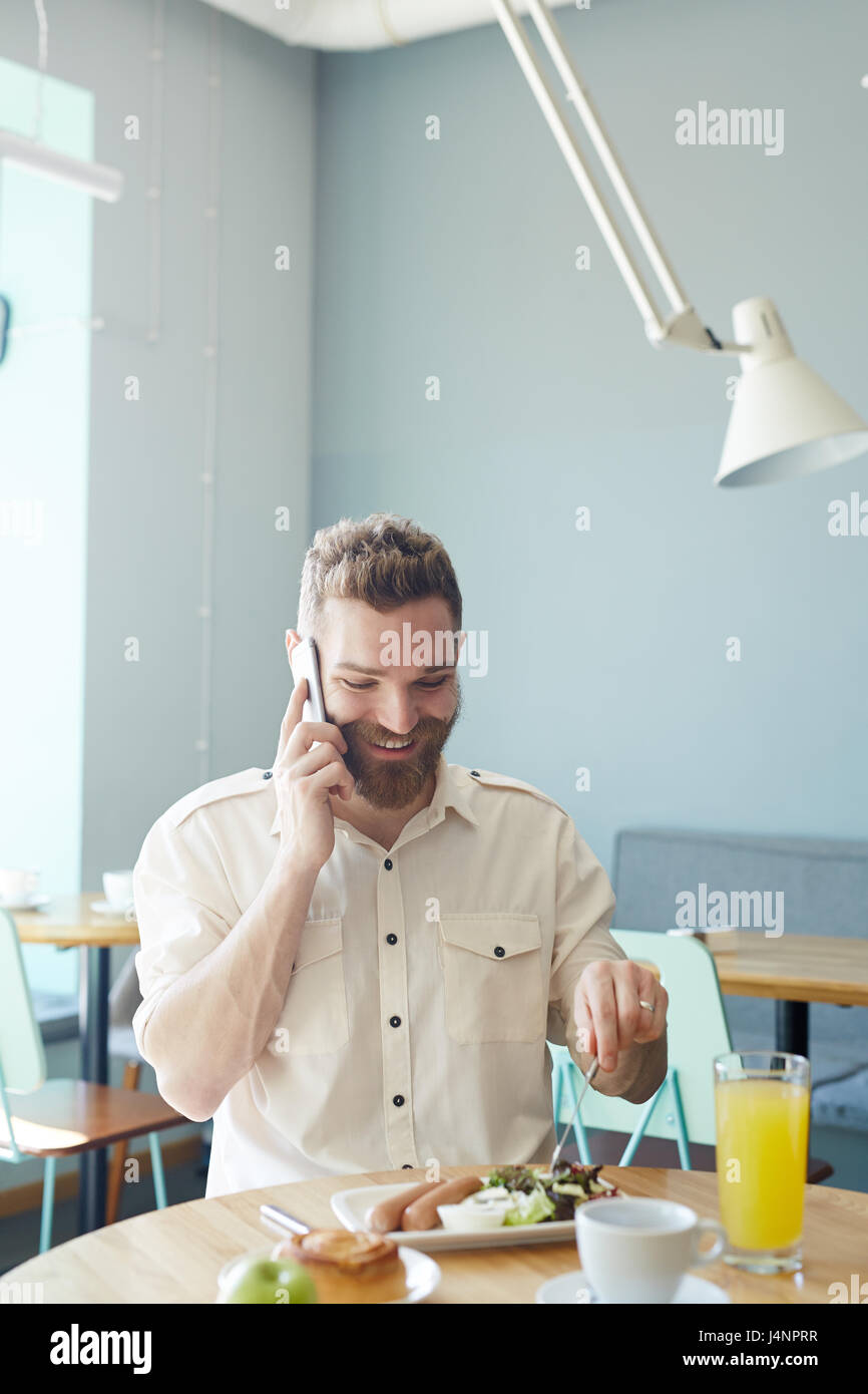 Happy ceo talking by cellphone and eating breakfast Stock Photo - Alamy