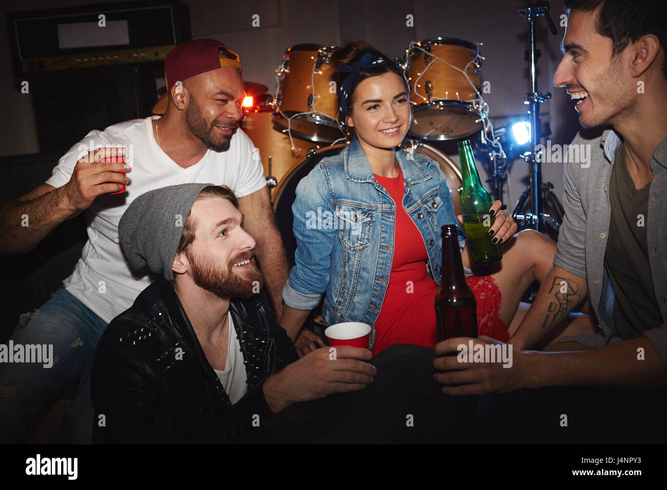 Contemporary young people, three men and woman, partying in night club ...