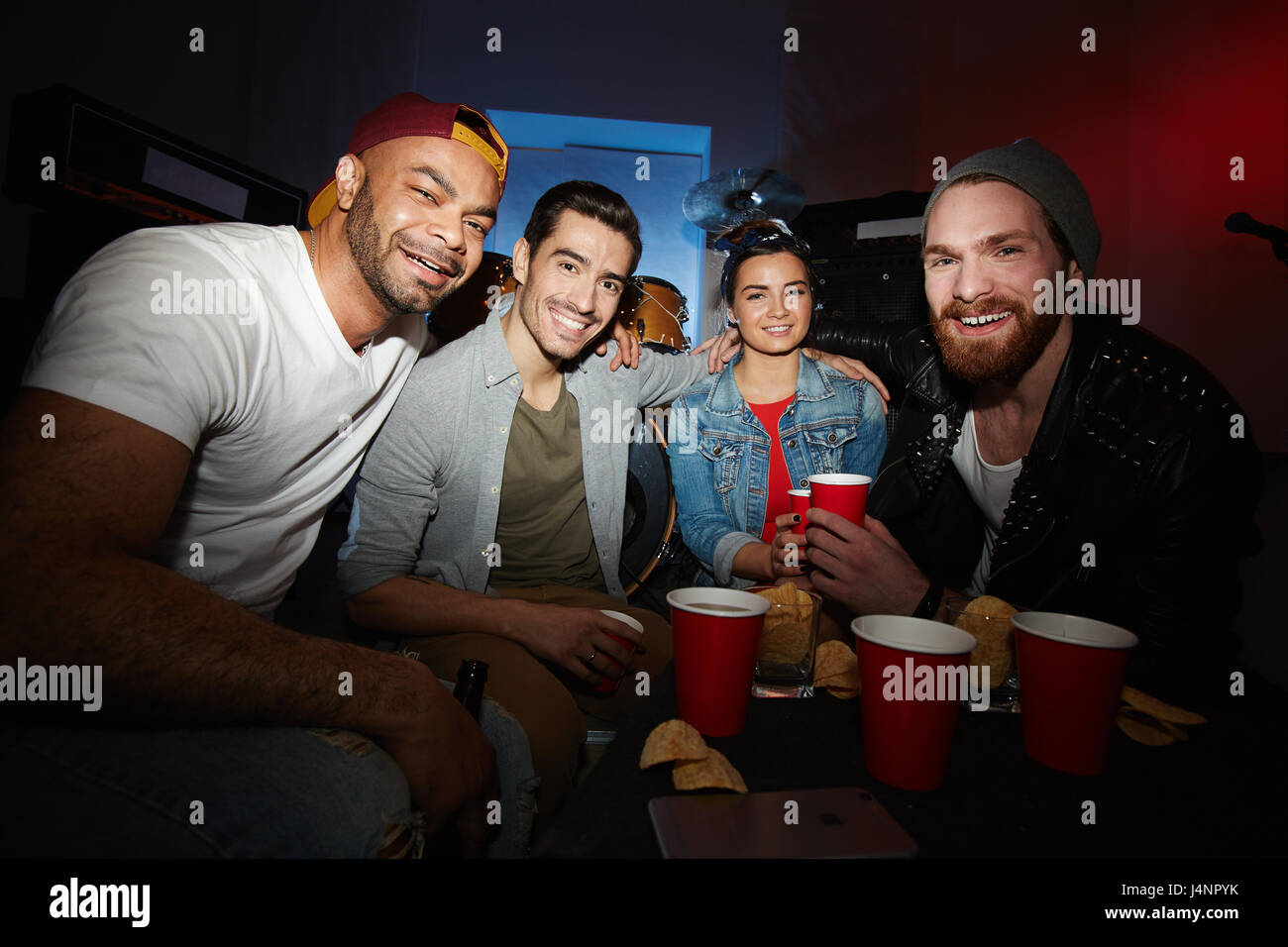 Group of modern trendy people chilling in night club, drinking beer and ...