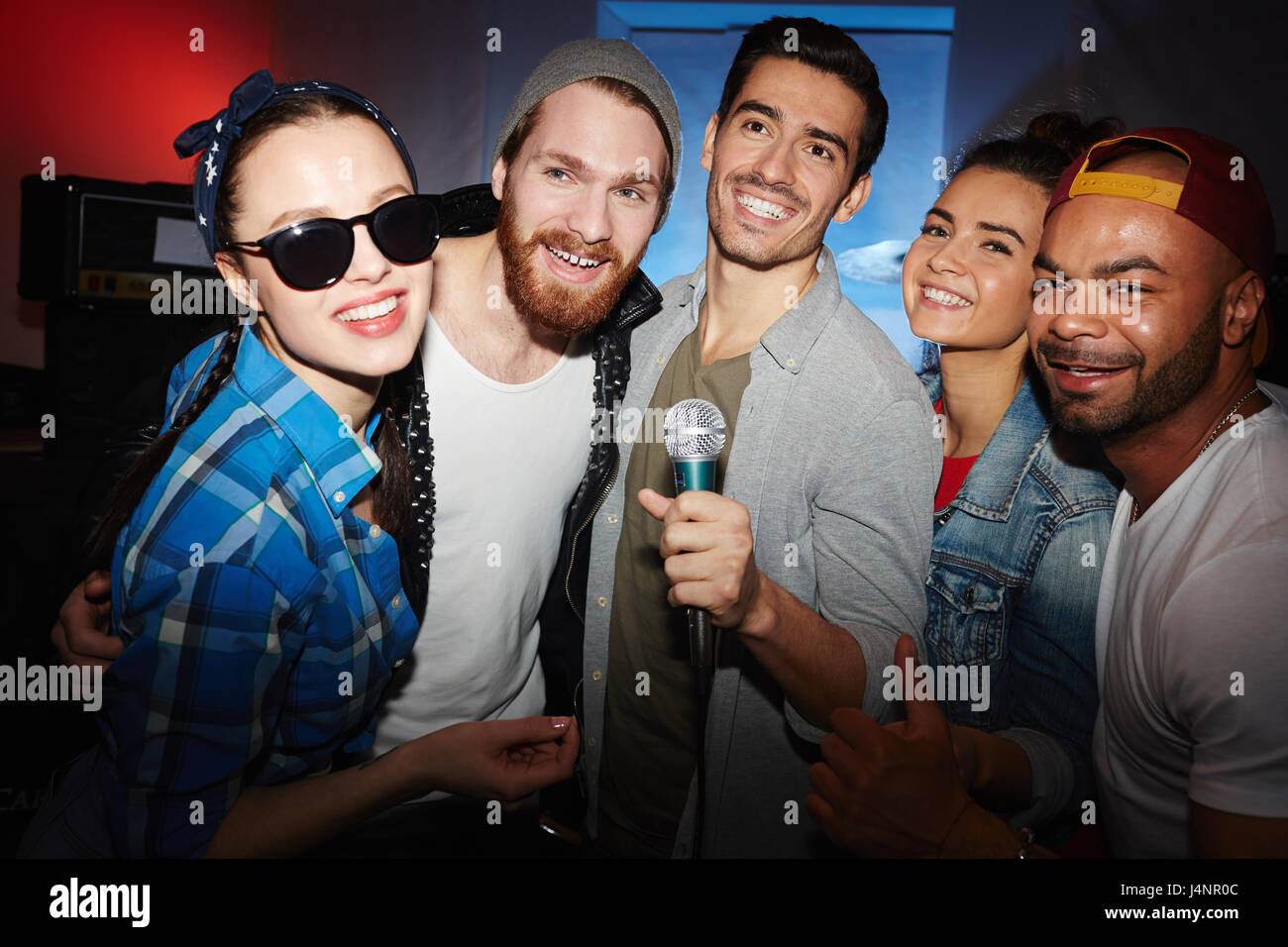 Multi-ethnic group of smiling young people hanging out in nightclub ...
