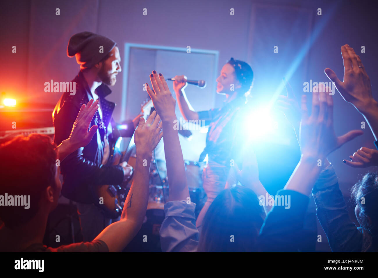 Local rock band performing music on stage of urban club with crowd ...