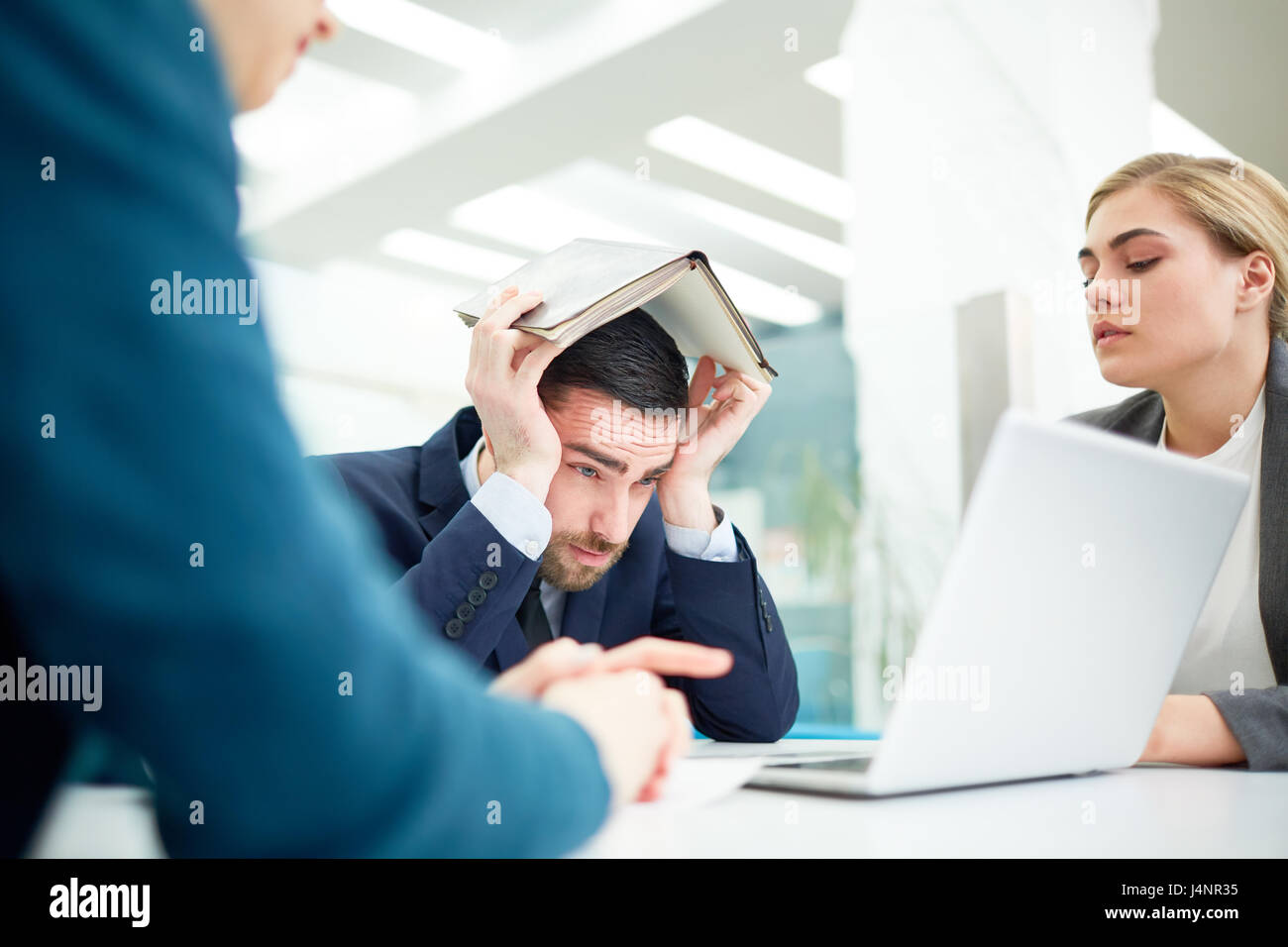 Confused businessman looking at laptop display with his colleagues near ...
