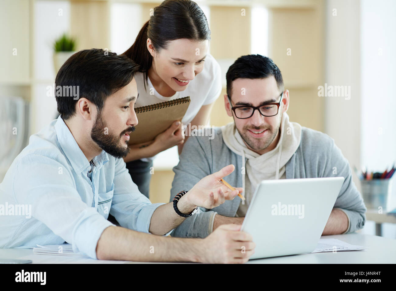 Group of employees looking at data in laptop Stock Photo - Alamy