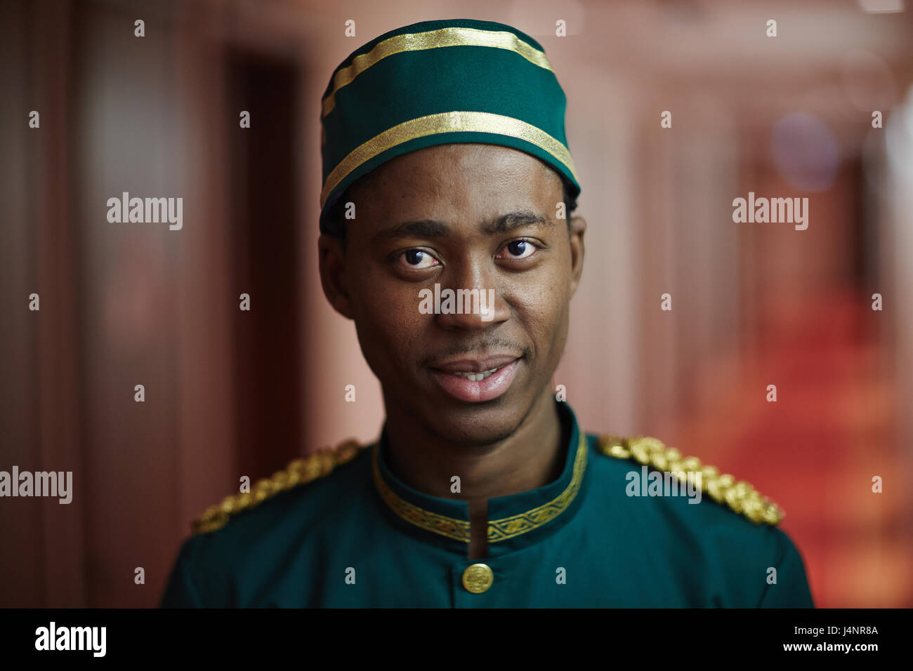 Portrait of smiling young bellhop of African ethnicity working in hotel ...