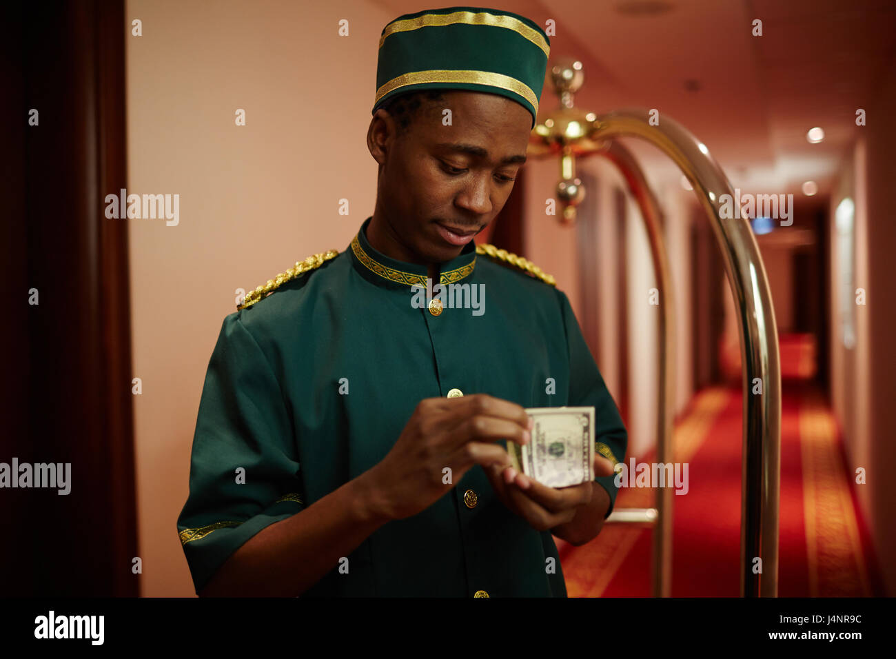 Portrait of young African boy working as bellhop in luxury hotel ...