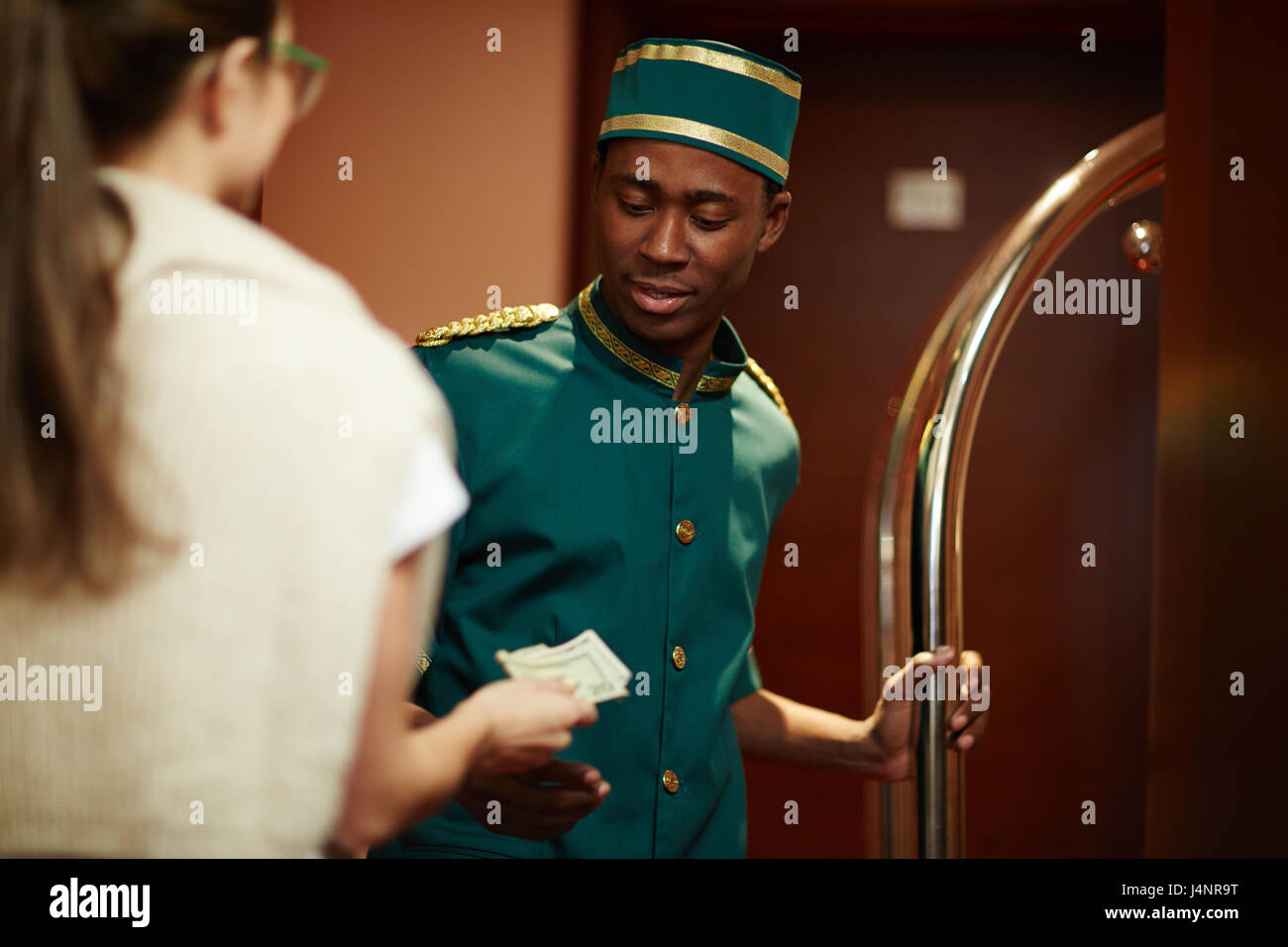 Portrait of smiling young African boy working as bellhop in luxury ...