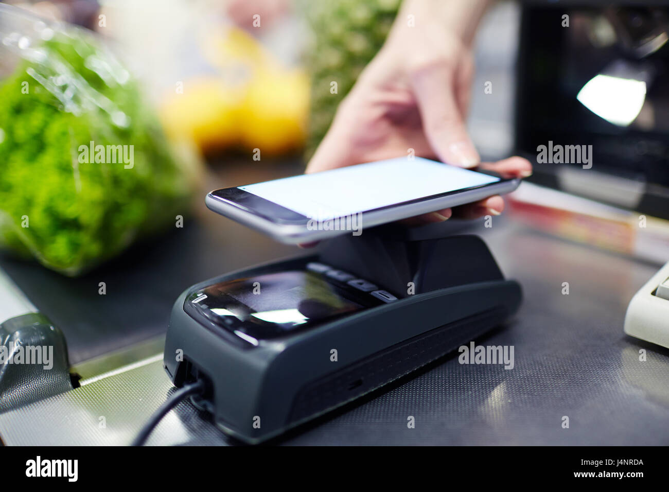Closeup shot of female hand holding smartphone over terminal using NFC ...