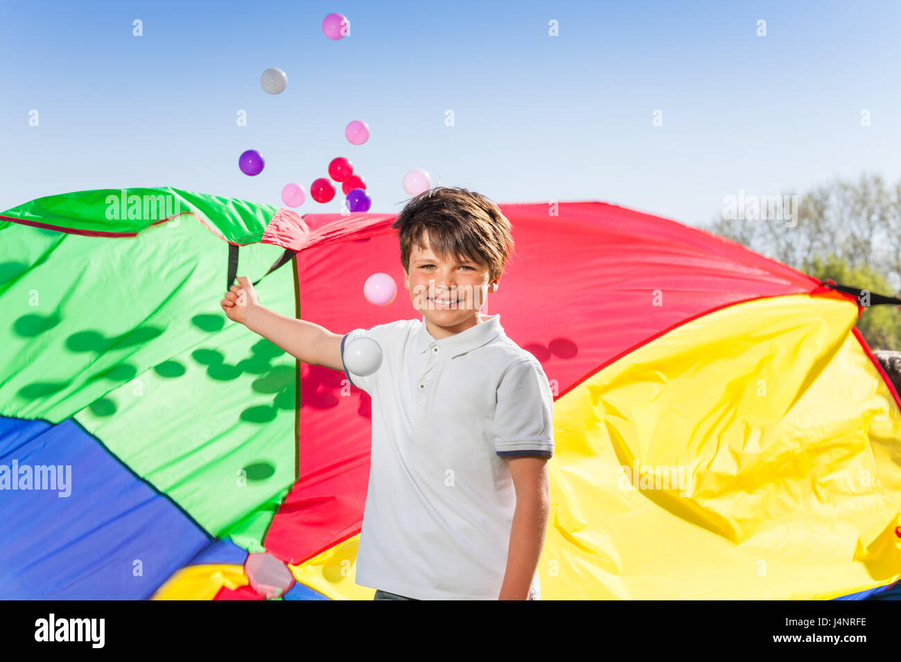 Portrait of happy Caucasian boy playing with a colorful parachute ...