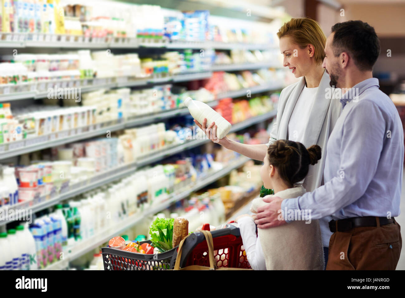 Portrait of happy family shopping in grocery store: buying milk in ...