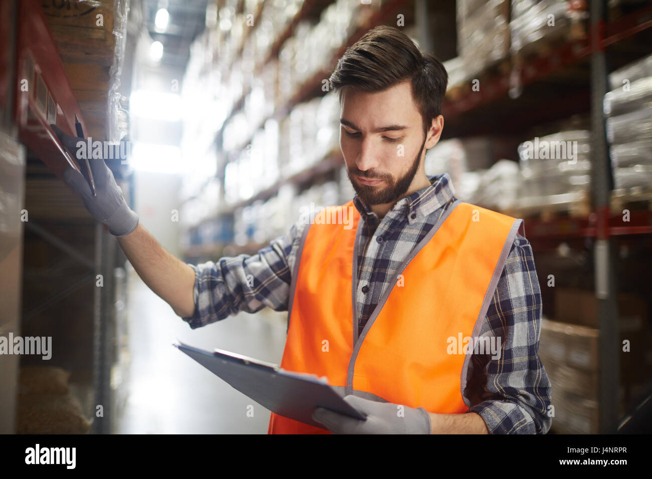 Serious warehouse worker checking up goods on shelves Stock Photo - Alamy