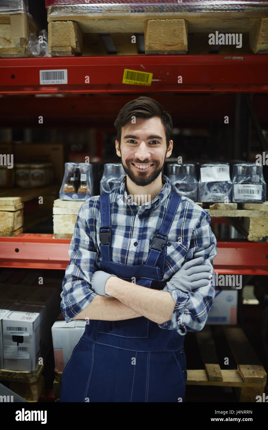 Successful warehouse worker standing by shelf with packed goods Stock ...
