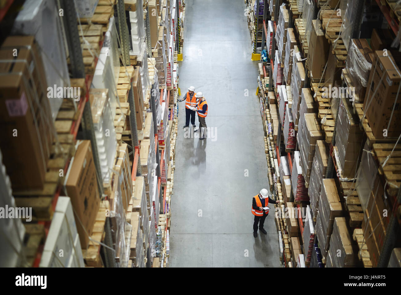 Group of workers in aisle between shelves with packed goods Stock Photo ...