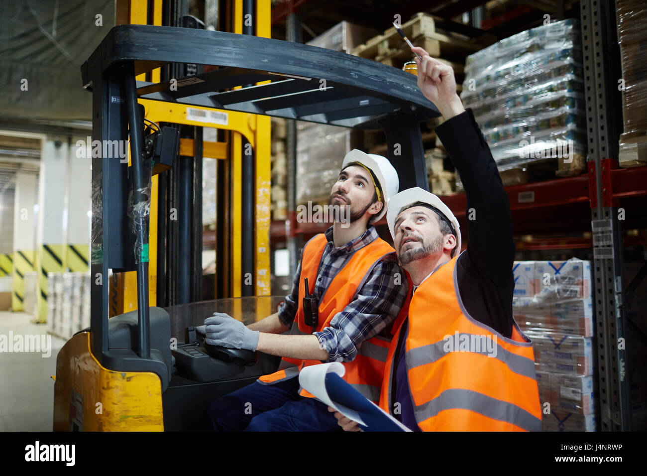 Two loaders trying to take goods from one of upper shelves Stock Photo ...