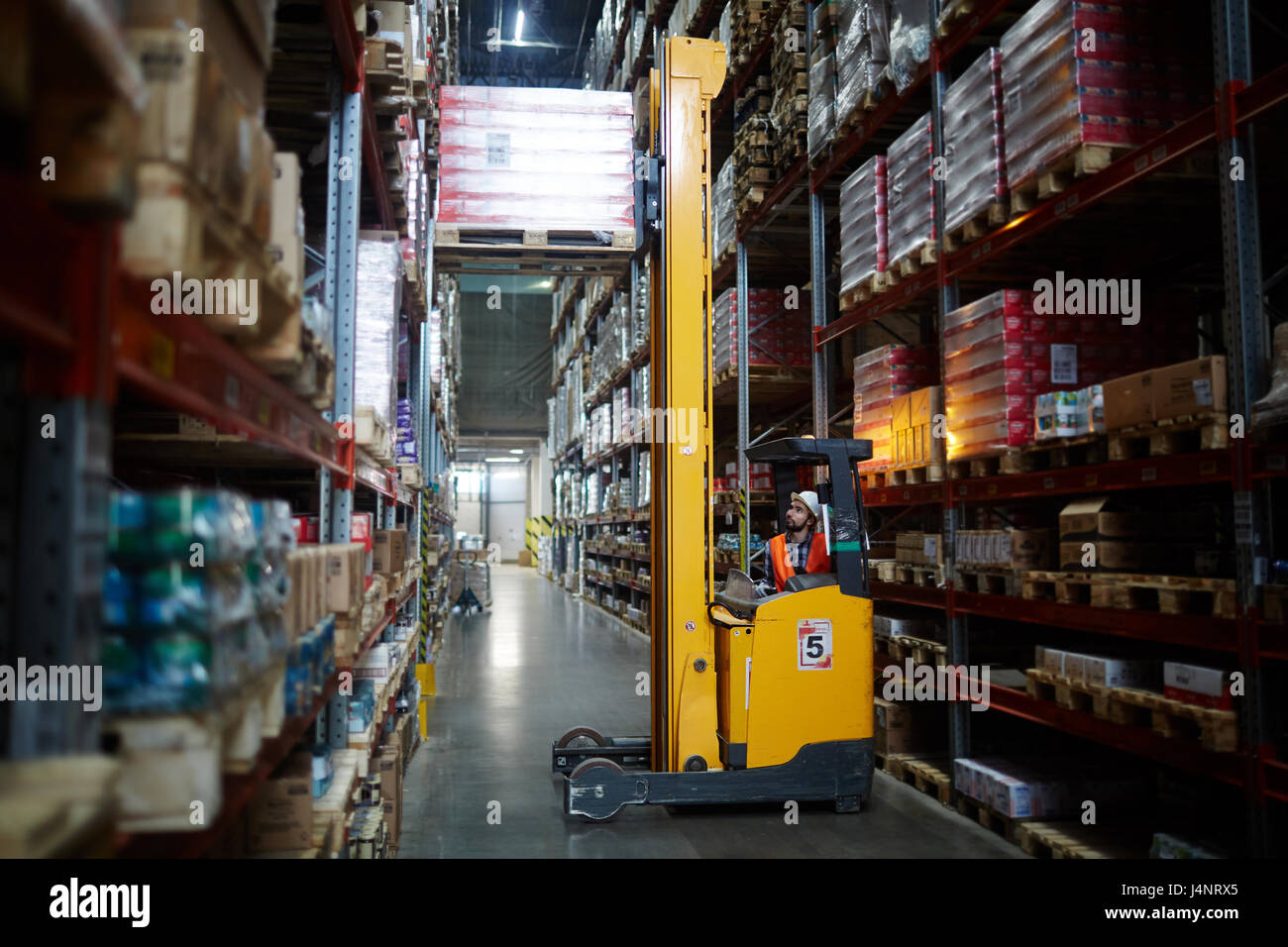 Loader lifting heavy cargo in warehouse Stock Photo - Alamy