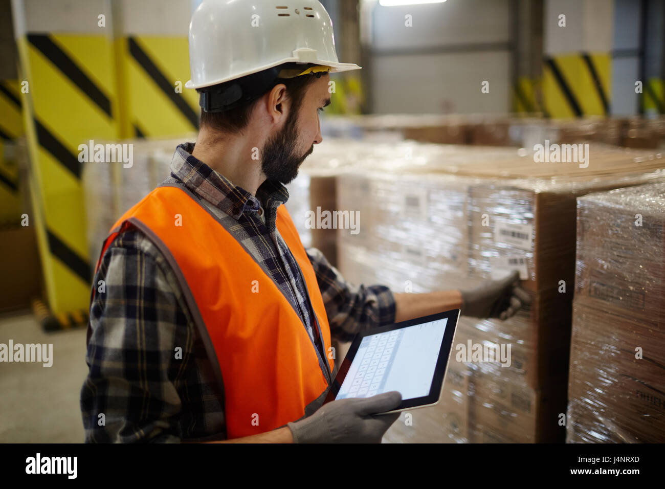 Dispatcher in uniform and helmet checking barcodes on packages Stock ...