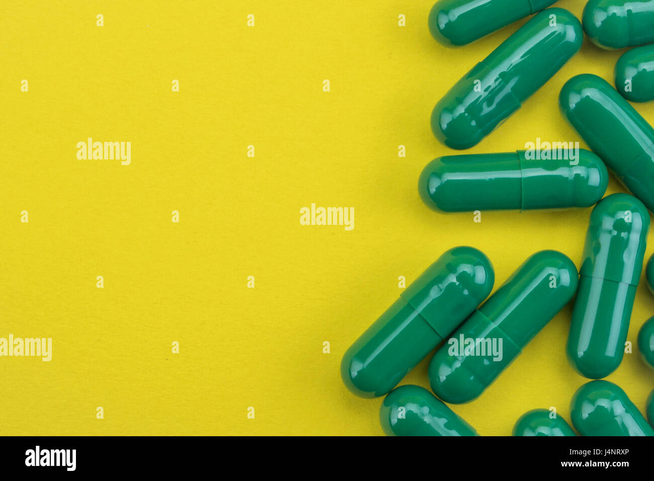 Green pills capsules medicine on yellow background Stock Photo - Alamy