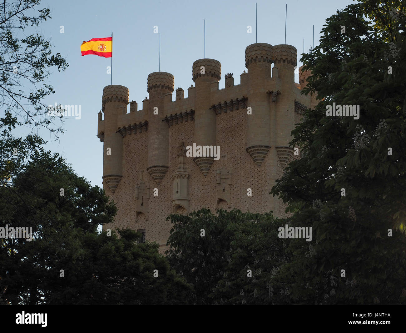 a view of Segovia Castle in silhouette with lit up Spanish flag flying ...