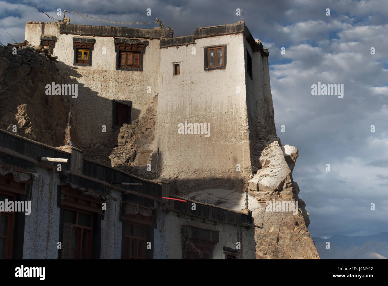 Traditional Tibetan house on the rock: high white wall, at the top of ...