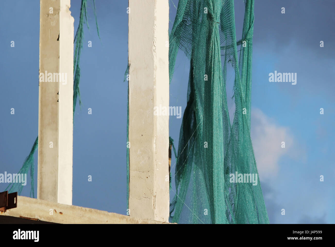 Torn green building mesh on an unguarded unfinished abandoned building ...