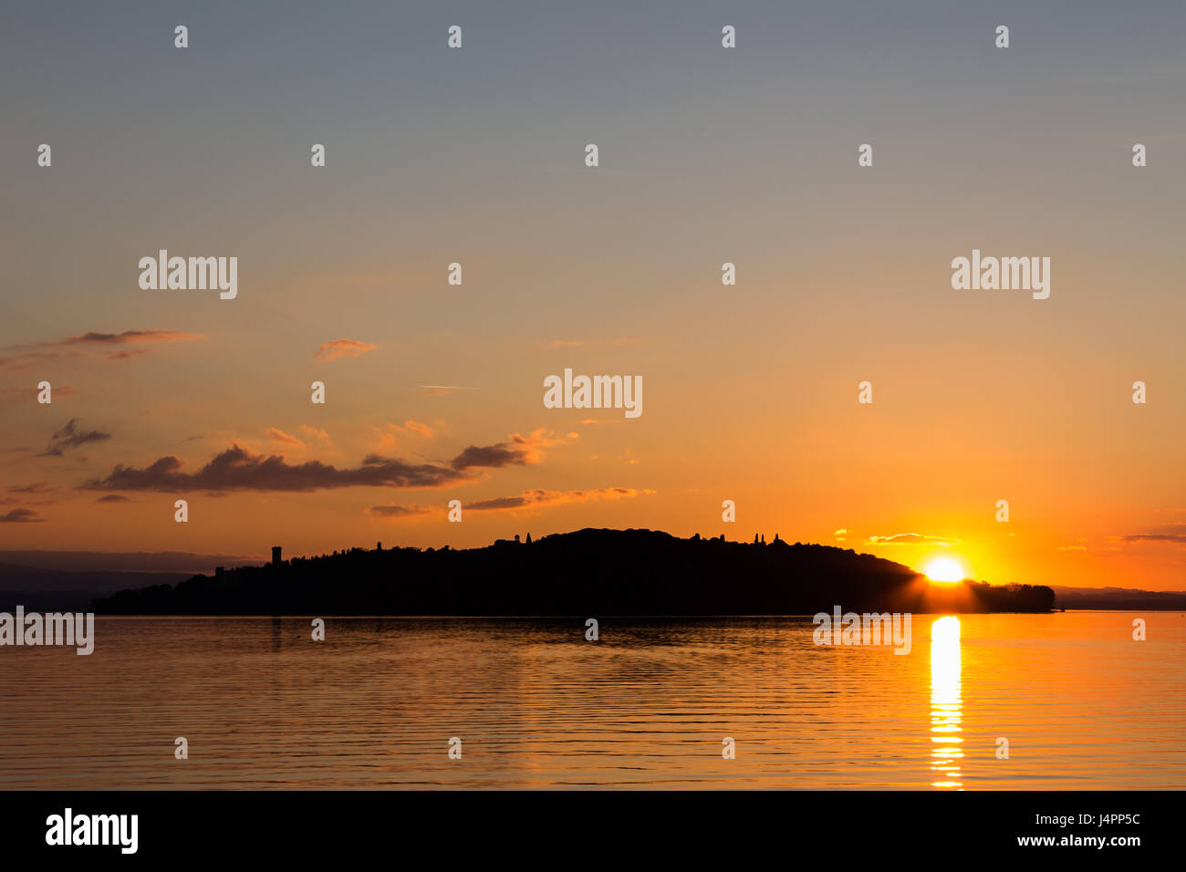 Beautiful sunset at the lake, with the sun coming down behind an island ...