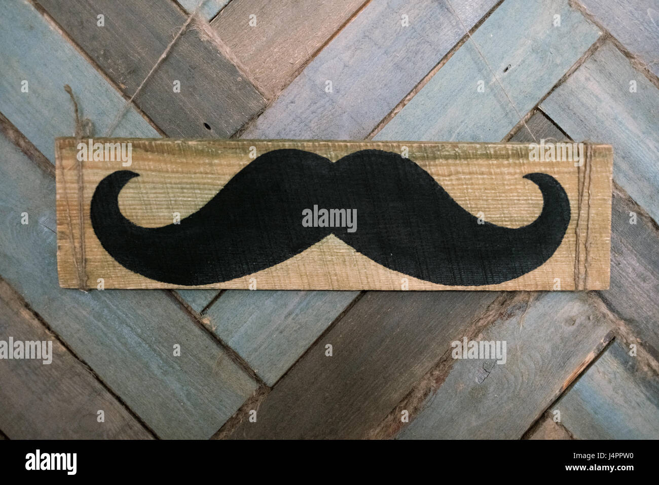A wooden sign with a mustache on the background of wooden wall ...