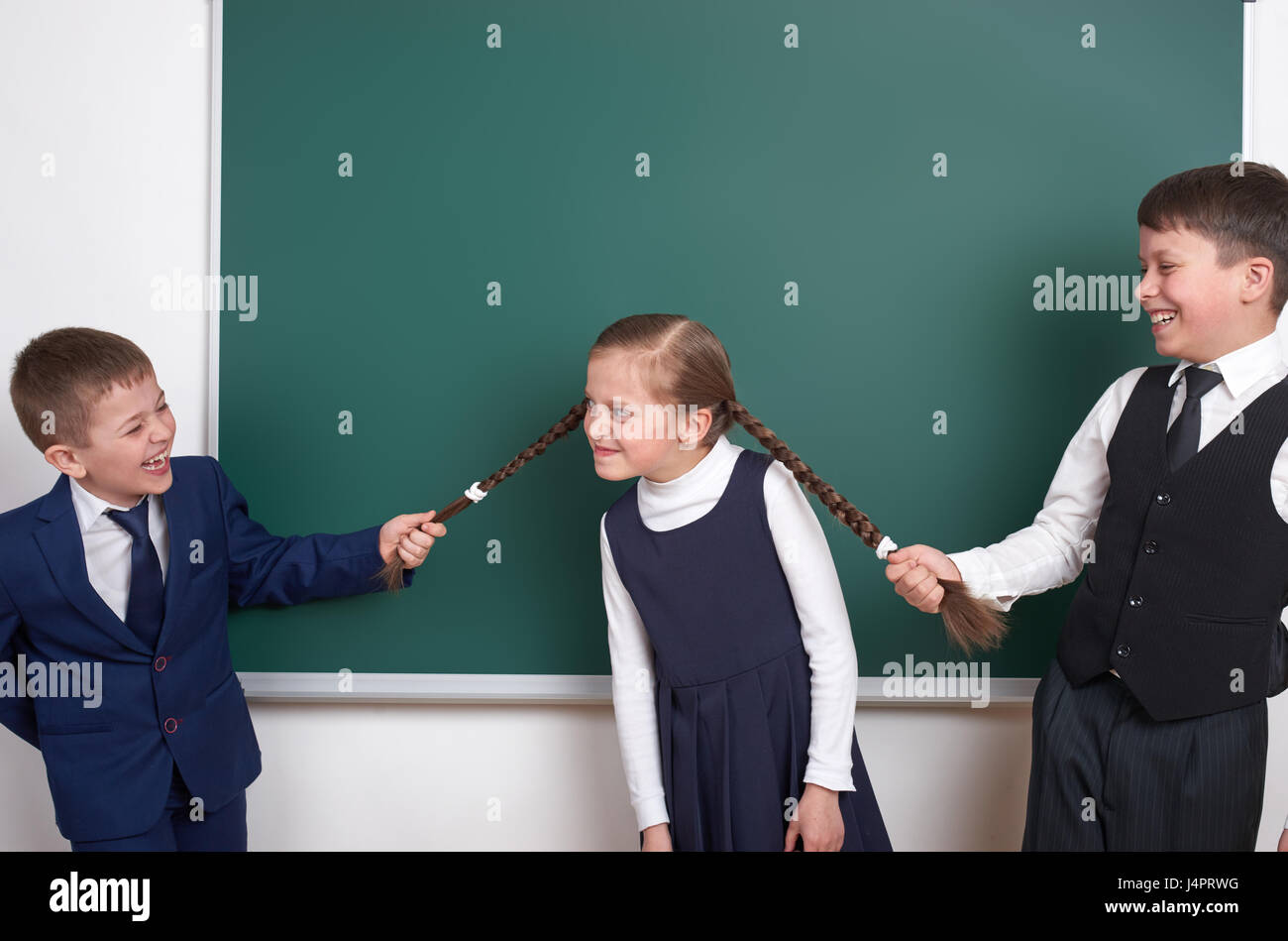 child play and having fun, boys pull the girl braids, near blank school ...