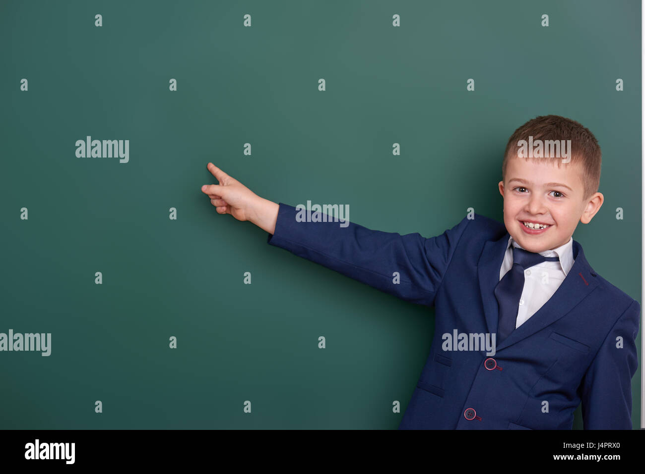 school boy point the finger near blank chalkboard background, dressed ...
