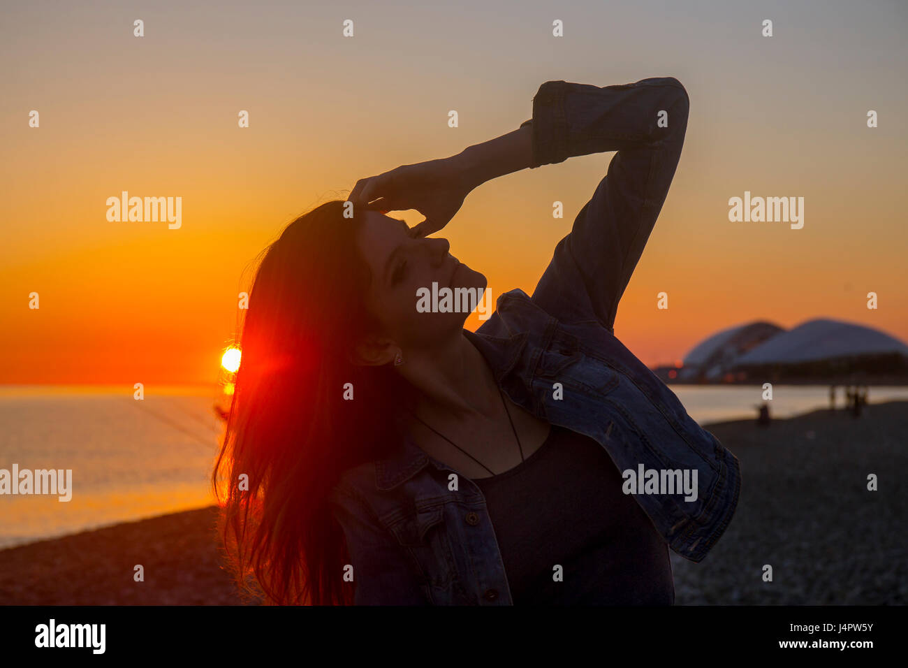 Young attractive woman on the beach at sunset time in backlight scene ...
