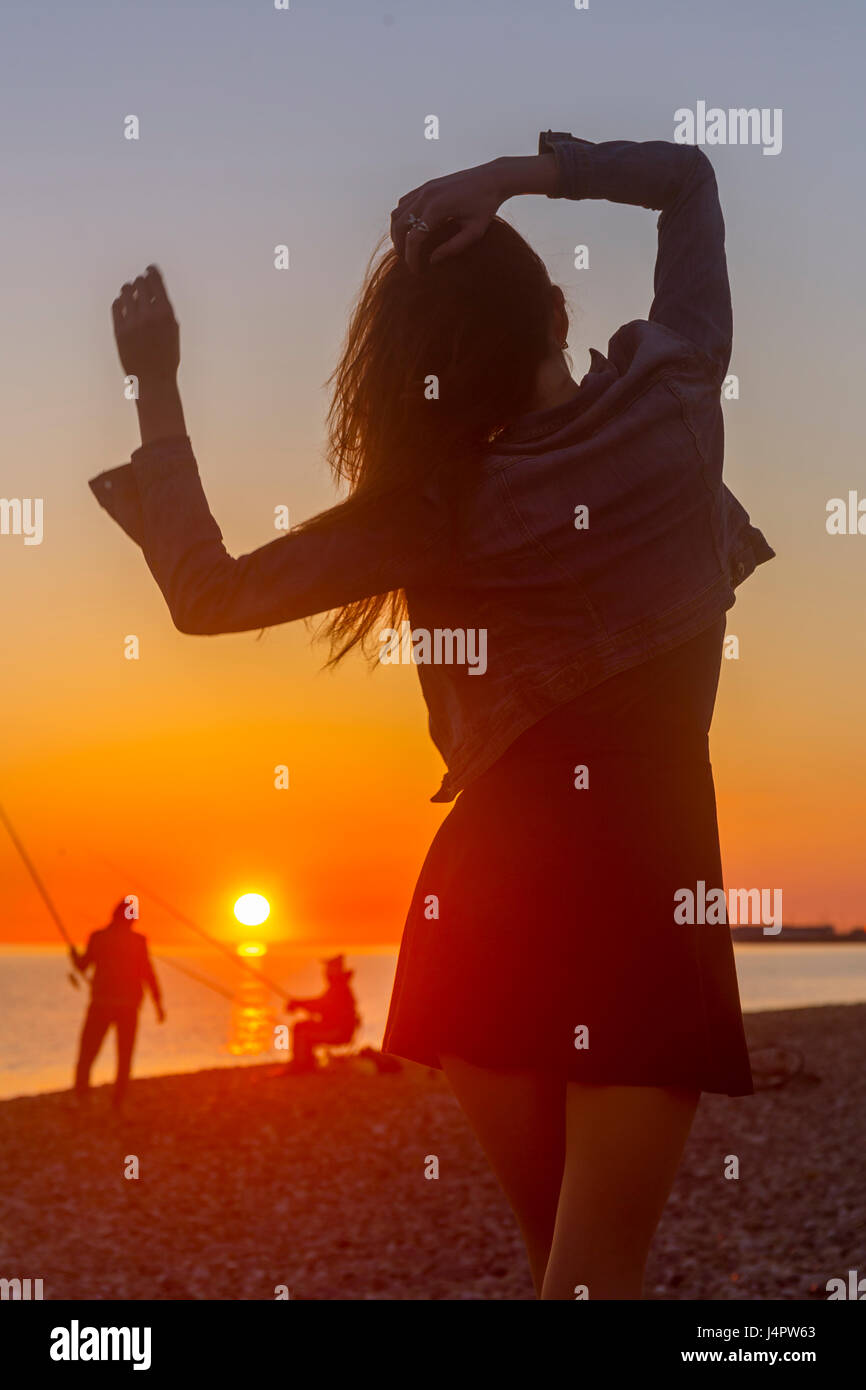 Young attractive woman on the beach at sunset time in backlight scene ...