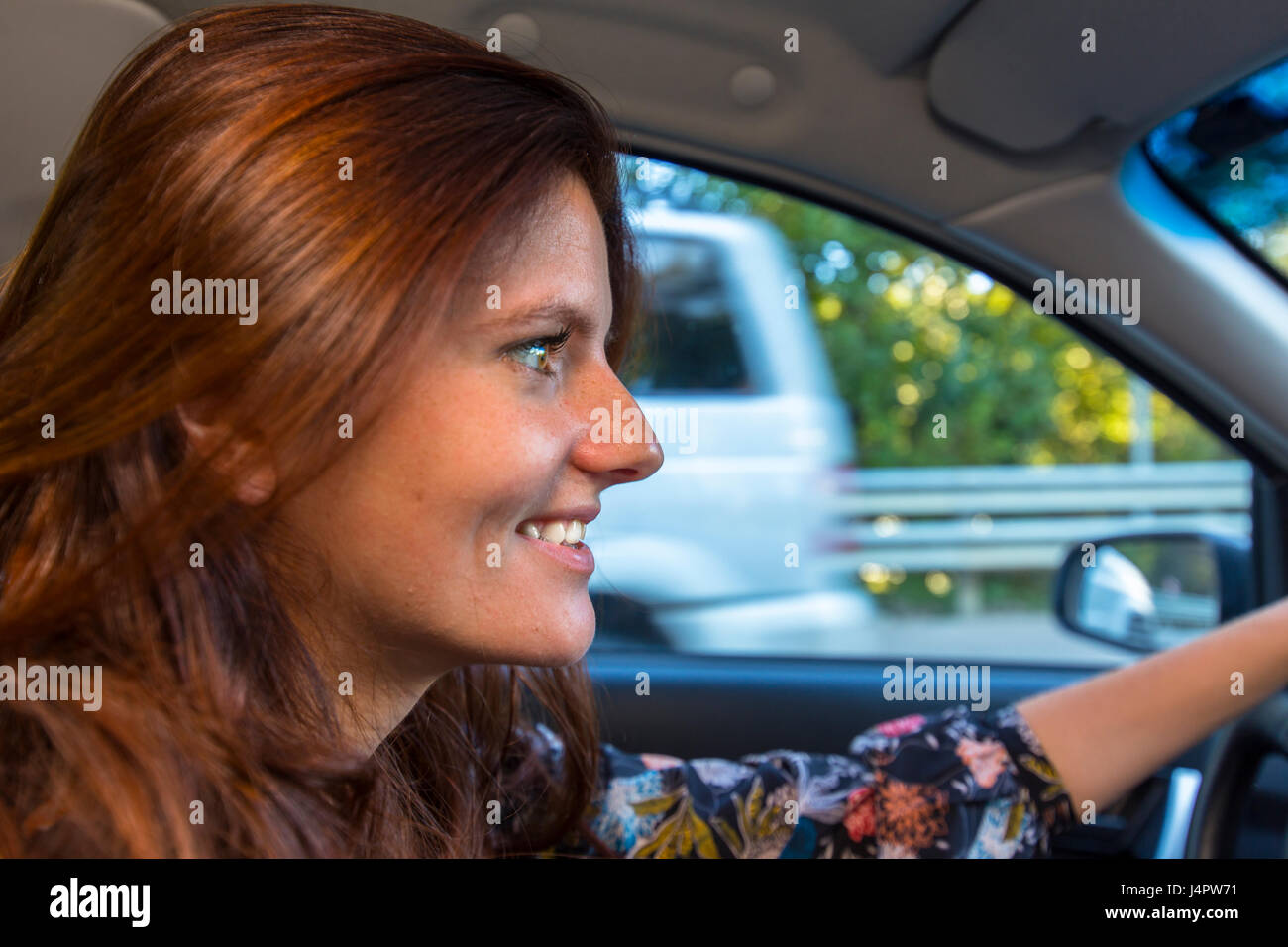 Attractive young woman driving car and smiling Stock Photo - Alamy
