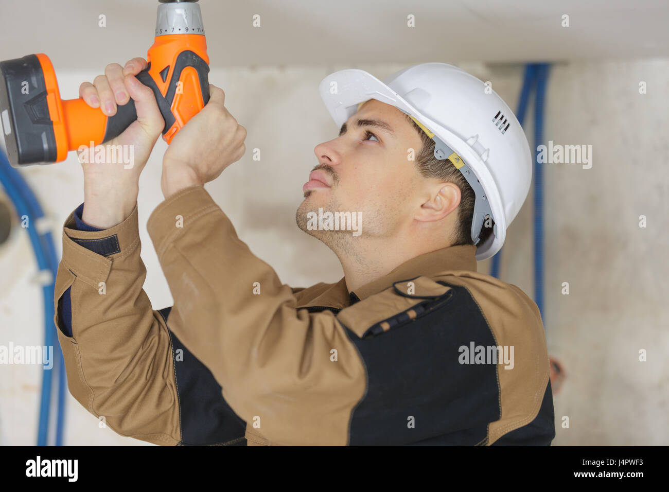 young man drilling a hole in white ceiling Stock Photo - Alamy