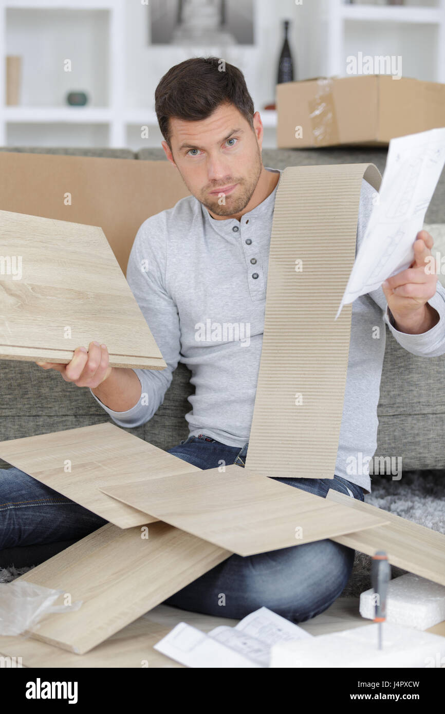 frustrated man putting together self assembly furniture Stock Photo - Alamy