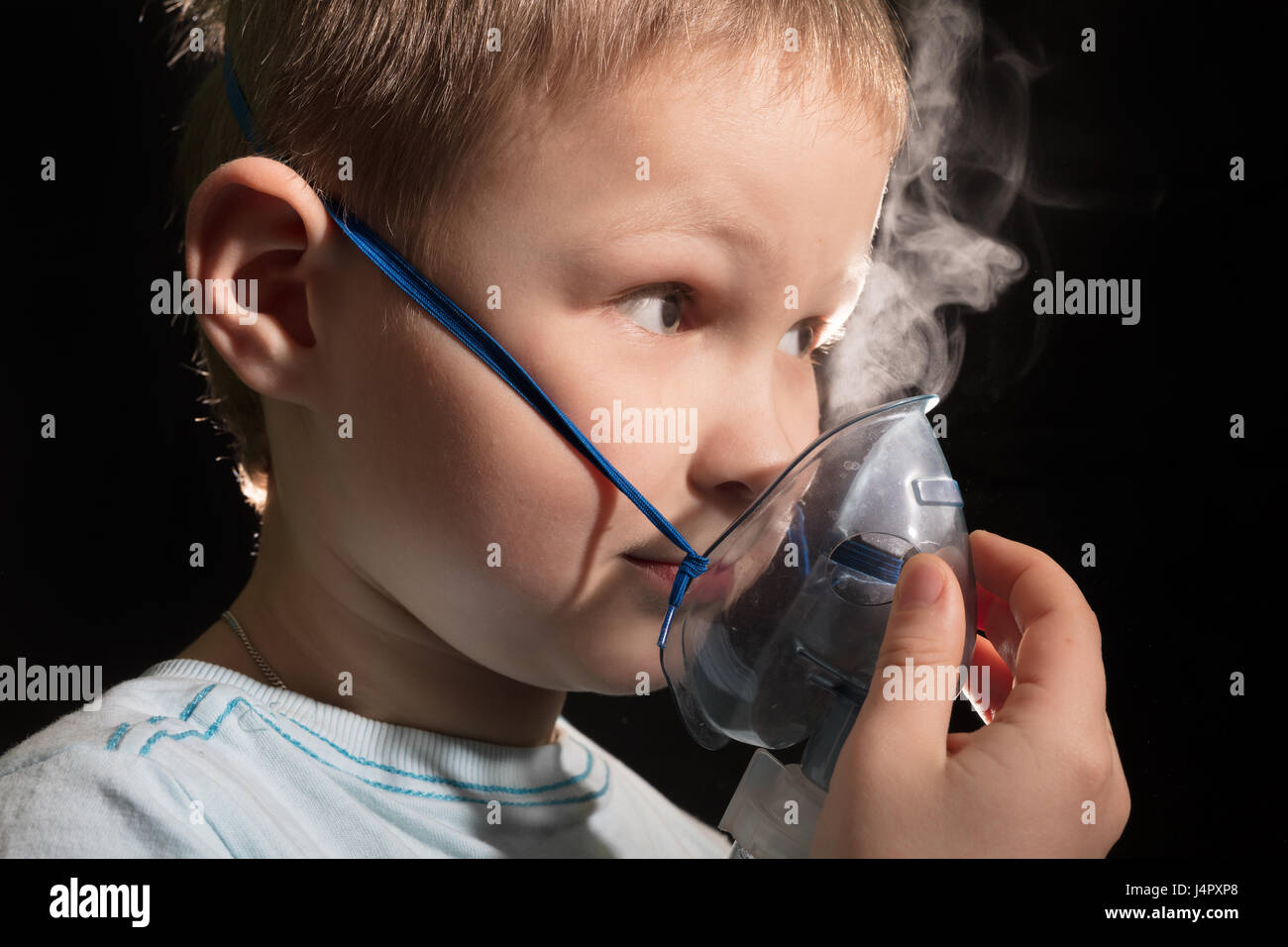 Kid breathing through nebulizer mask on black background Stock Photo ...