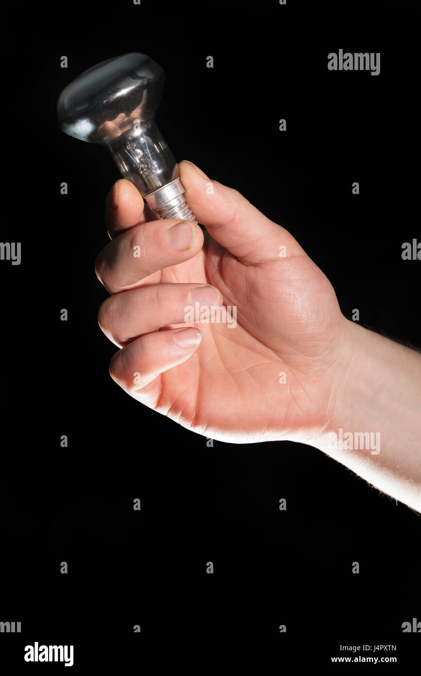 Man's hand holding electrical lamp on black background Stock Photo - Alamy