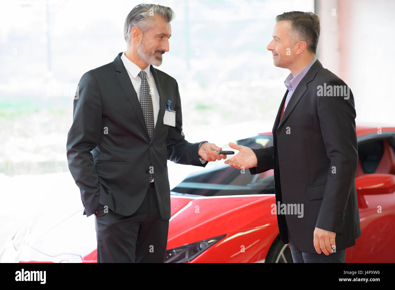 Salesman handing sports car keys to customer Stock Photo - Alamy