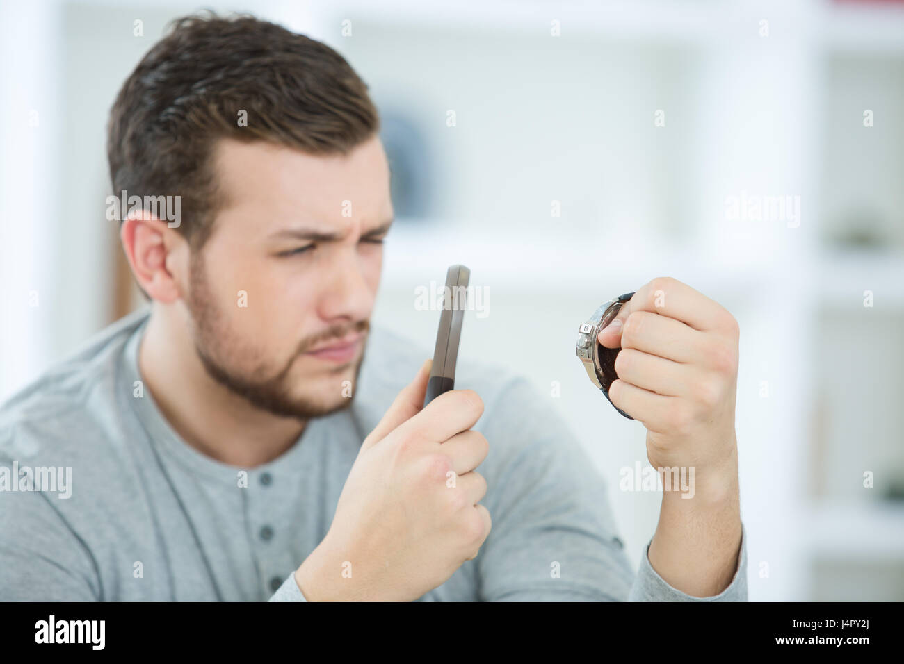 young man looking at watch through magnifying glass Stock Photo - Alamy