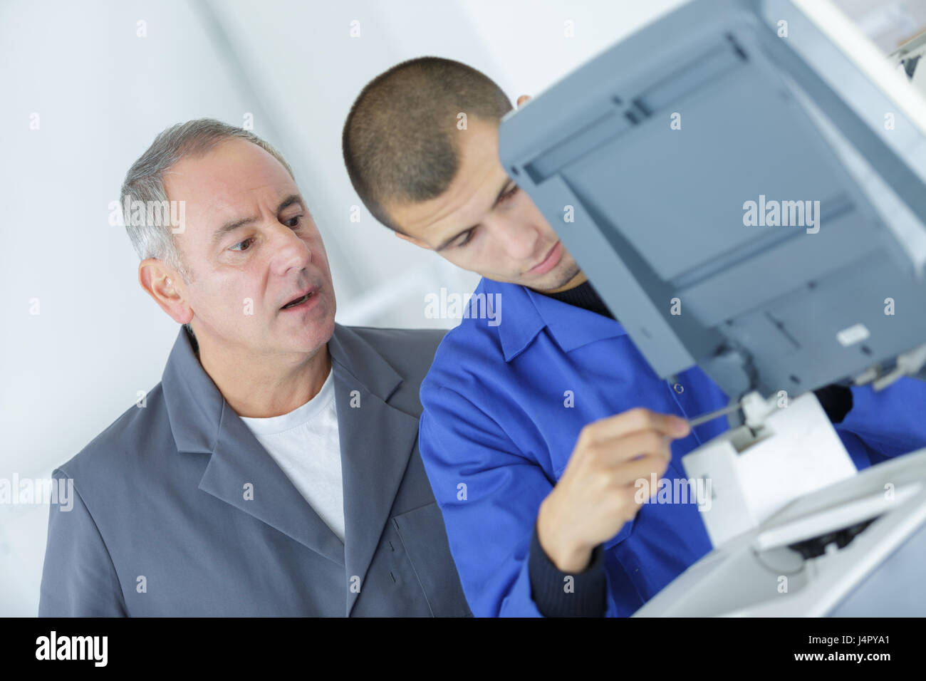Supervisor watching young technician at work Stock Photo - Alamy