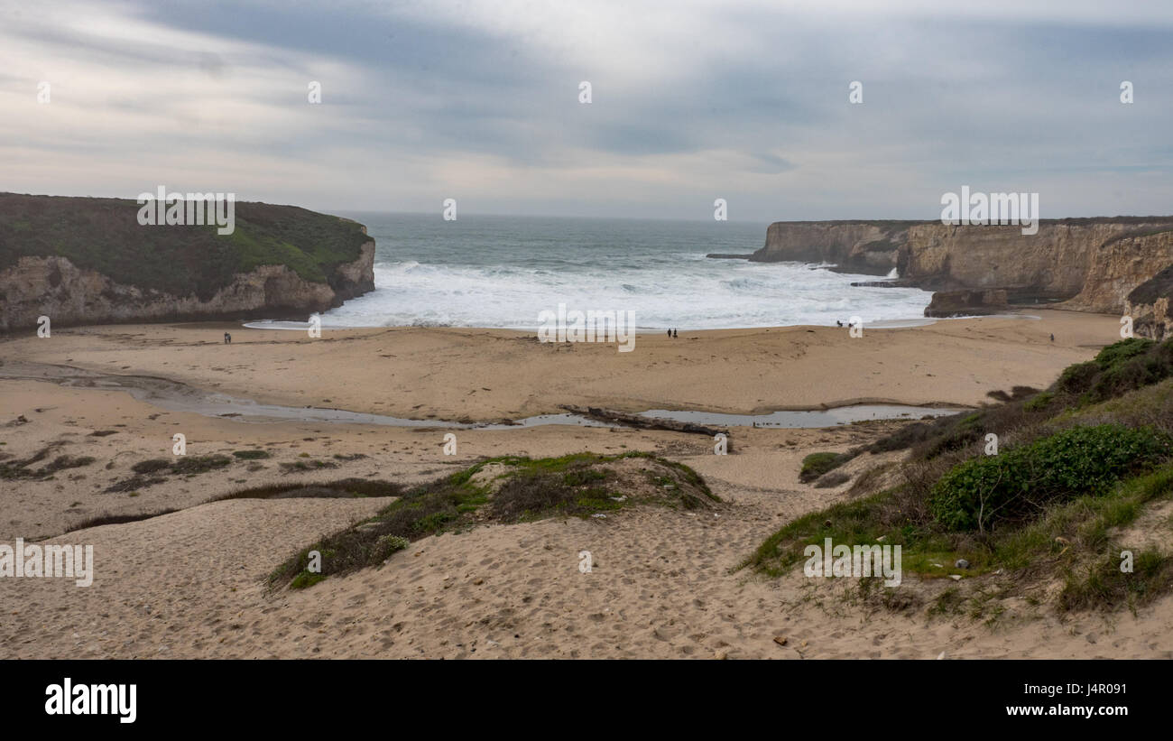 Beach in Between Cliffs with Cloudy Skies Stock Photo - Alamy