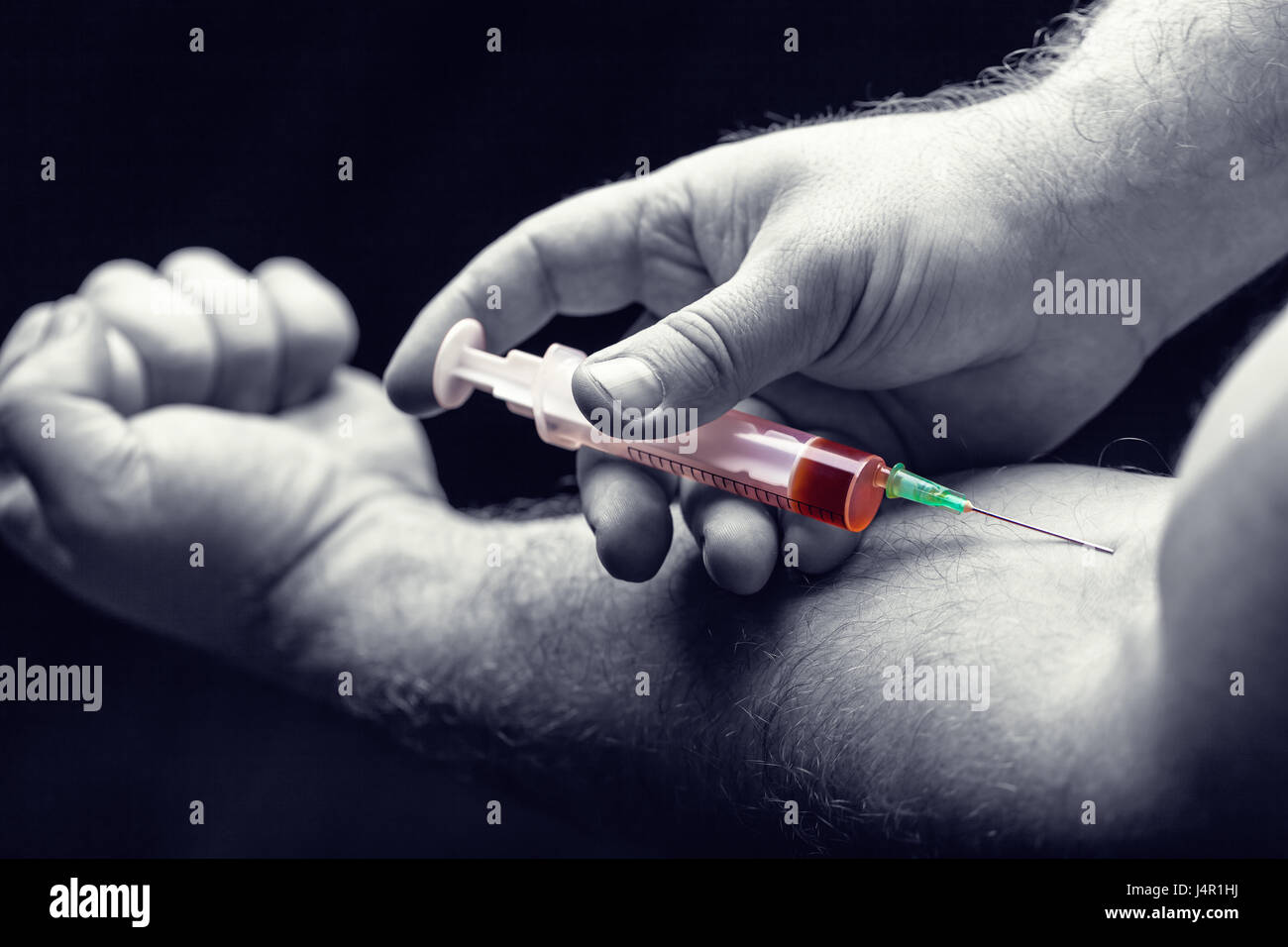 Close- up drug addict strong man with syringe in action on dark ...