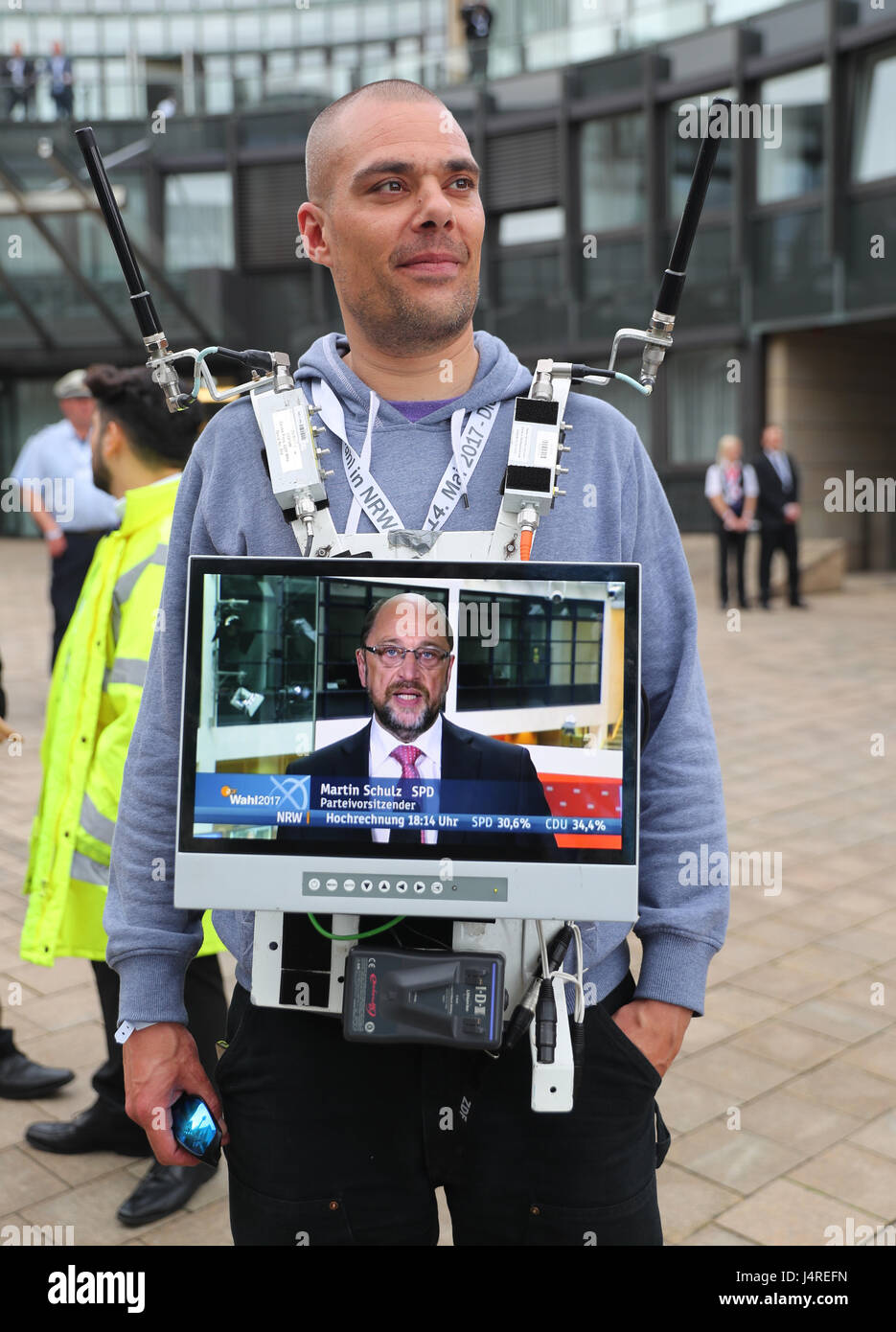 A TV employee wearing a monitor featuring a live image of SPD leader ...