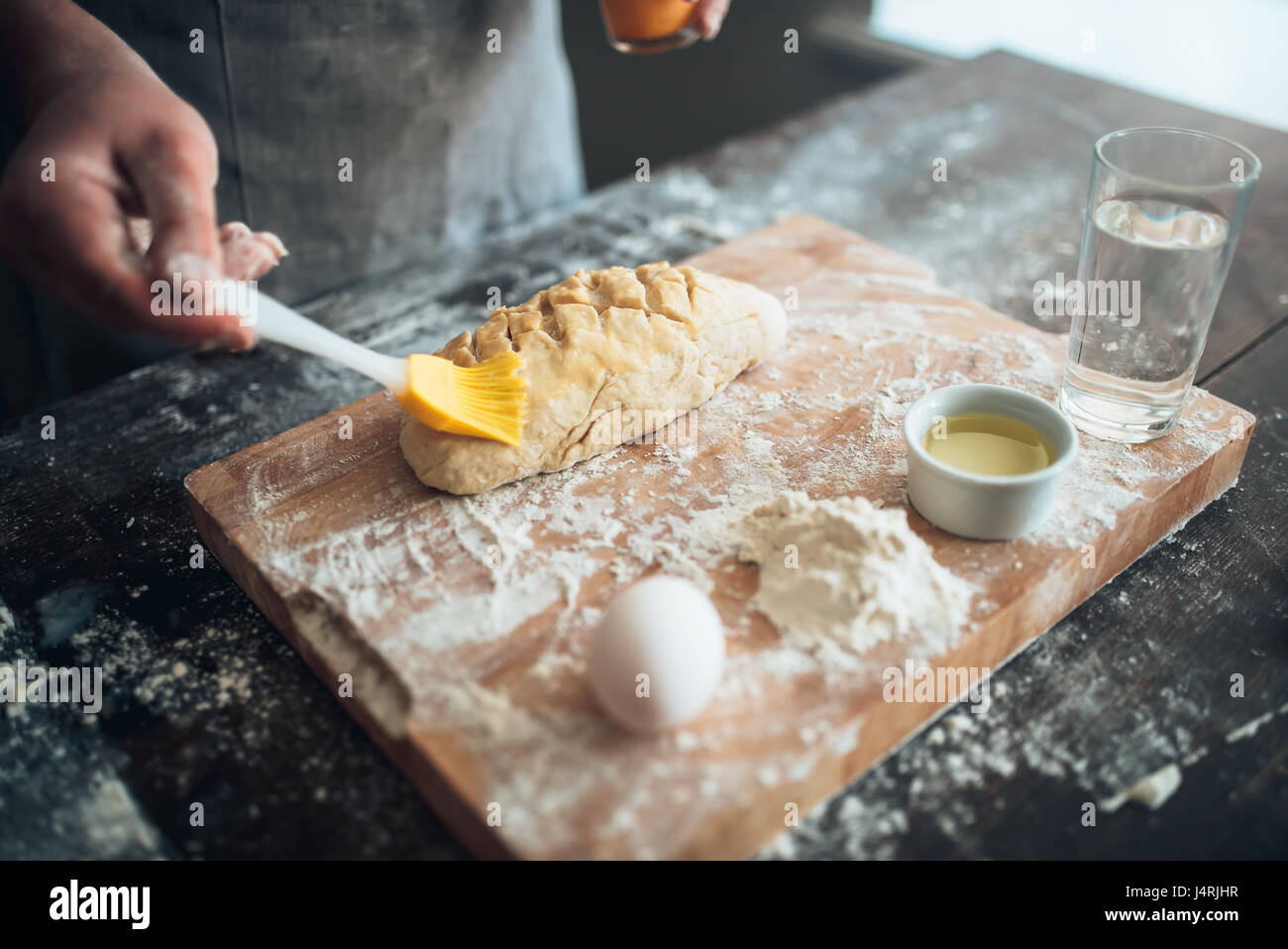 Baker hands smears butter on bread dough. Bread preparation on cutting ...